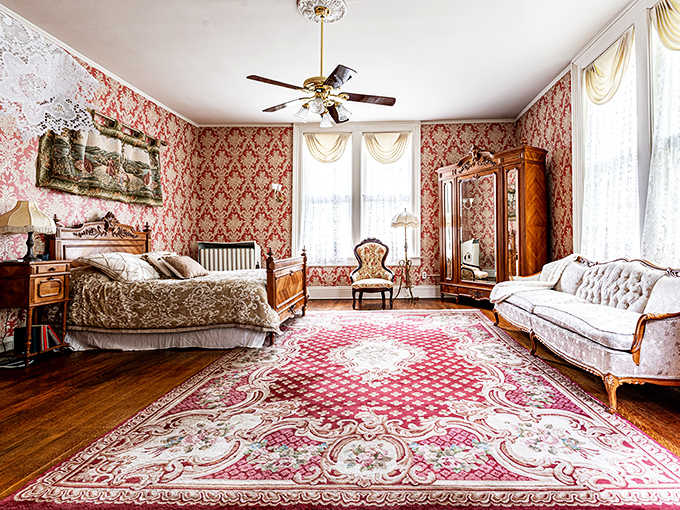 Rose-patterned wallpaper embraces antique furniture in a room so authentically Victorian, you half-expect to find a corset in the dresser.