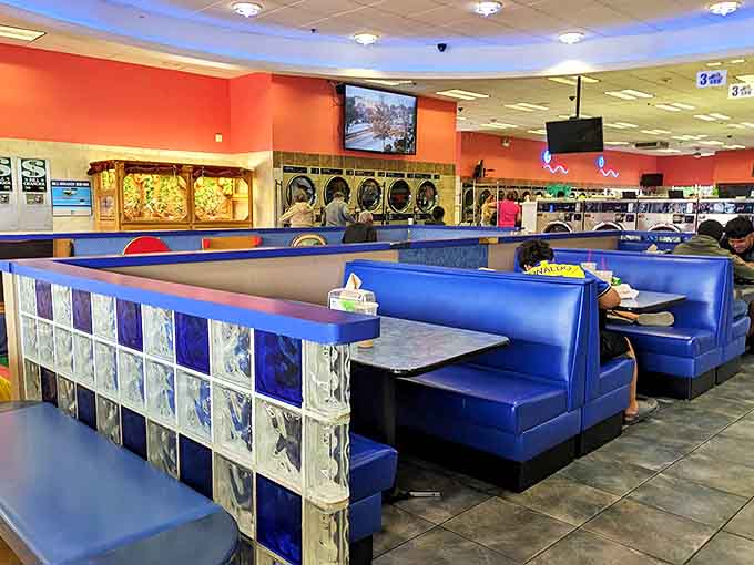 Retro diner-style booths with glass block accents offer cozy islands of comfort amid the sea of laundry activity.