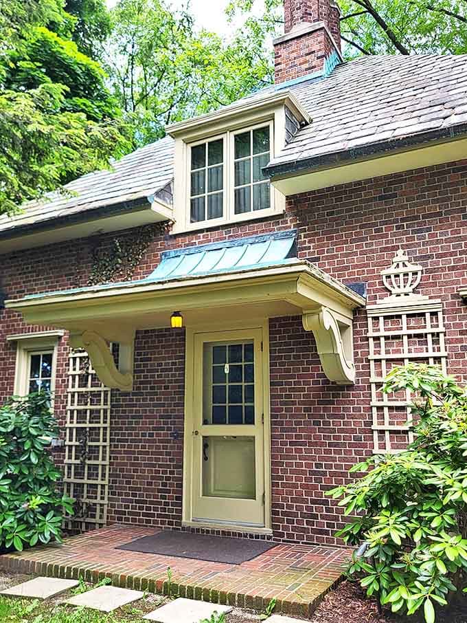 This charming cottage doorway, with its copper awning and lattice details, invites curiosity about who might have lived within these brick walls.