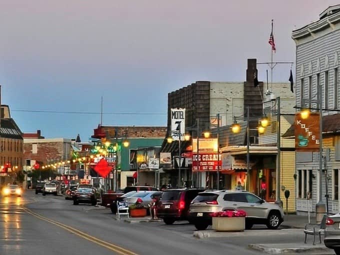 Evening lights illuminate downtown storefronts, creating that small-city charm where you can actually find parking and people still say hello to strangers on sidewalks.