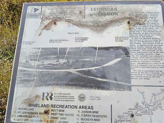 History comes alive through weathered information signs that tell the human stories behind the massive landscape transformations visible from the overlook.