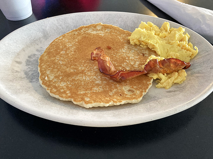 Simple perfection on a plate: a golden pancake, perfectly cooked eggs, and bacon that strikes the ideal balance between crisp and chewy.