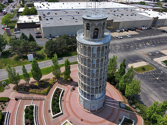 An aerial view reveals the tower's carefully designed plaza, with brick pathways creating geometric patterns that complement the circular structure.