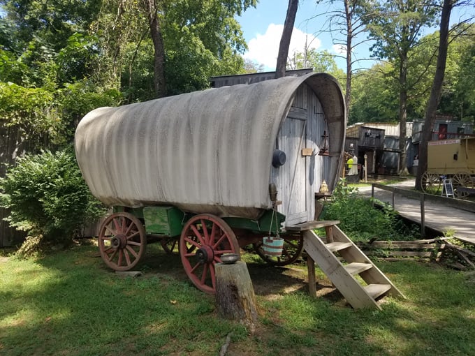 A classic covered wagon stands ready for the trail, its canvas top protecting precious cargo from sun and rain.