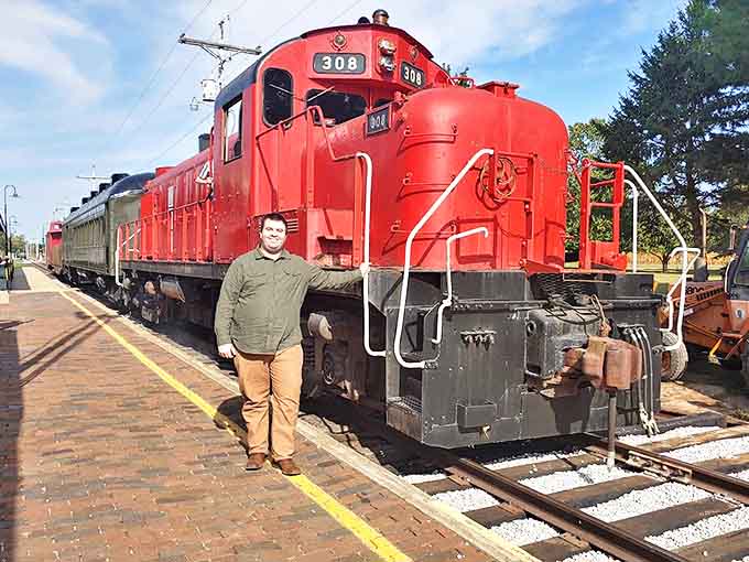 Generations connect as a visitor stands beside the mighty #308 locomotive, the size difference highlighting just how impressive these engineering marvels truly are.