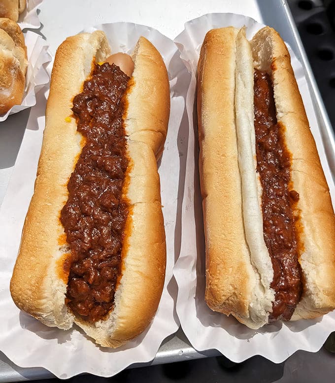 Chili dogs done right – these beauties come smothered in perfectly seasoned meat sauce, a messy but magnificent tribute to American drive-in culture.