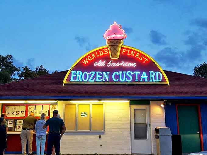 As dusk falls, World's Finest Frozen Custard's neon sign glows like a beacon for dessert lovers. The pink ice cream cone logo promises sweet relief after hot summer days.