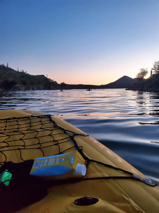 Sunset transforms Saguaro Lake into liquid gold, as kayakers glide across mirror-like waters beneath the fading desert light.