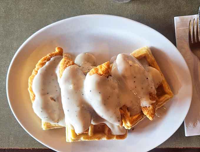 Chicken and waffles unite in a savory-sweet alliance, blanketed in country gravy that brings peace to the breakfast table.