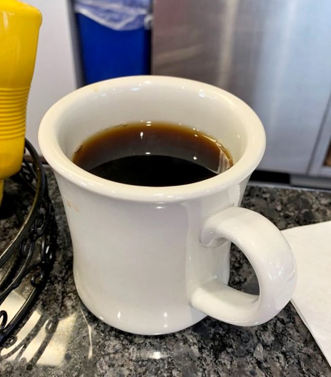That thick white mug doesn't just hold coffee—it cradles liquid motivation in ceramic simplicity, no fancy names required.