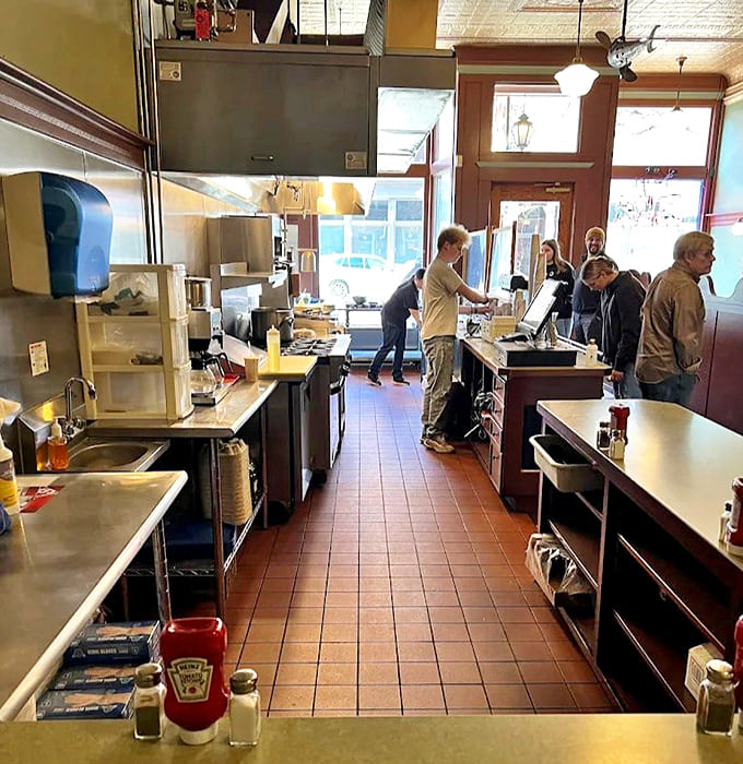 The narrow galley kitchen design allows diners to witness the choreographed efficiency that turns simple ingredients into legendary local fare that keeps Kalamazoo coming back.