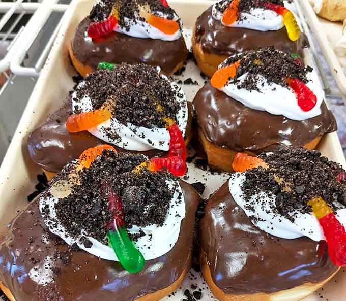 Chocolate-dipped donuts adorned with cookie crumbles and gummy worms &ndash; childhood nostalgia in edible form for the young and young-at-heart.