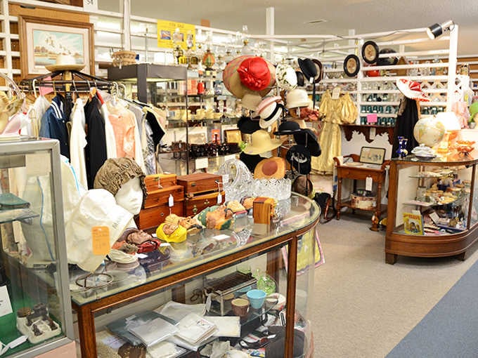 Mannequin heads model vintage hats while glass cases display treasures from bygone eras in this well-organized booth.