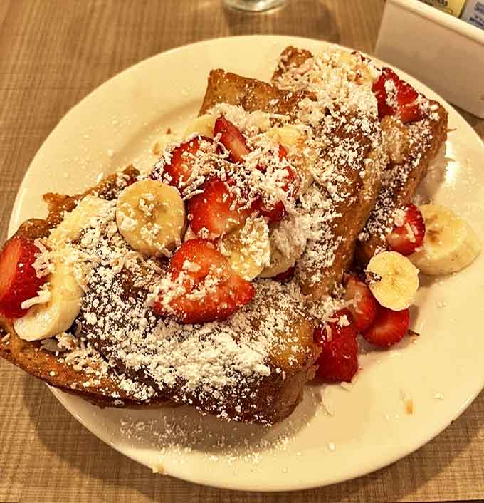 This French toast isn't just breakfast, it's dessert masquerading as a morning meal, crowned with fresh fruit and powdered sugar.