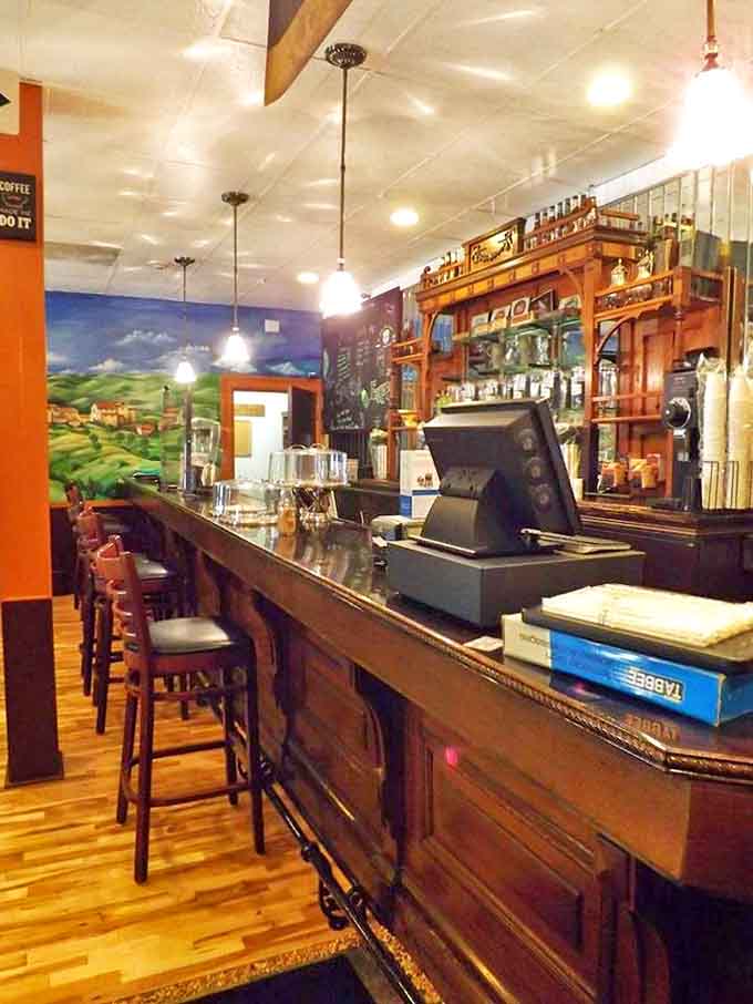 The bar area offers a front-row seat to culinary magic, with its beautiful wooden counter and pastoral mural creating a cozy vignette.