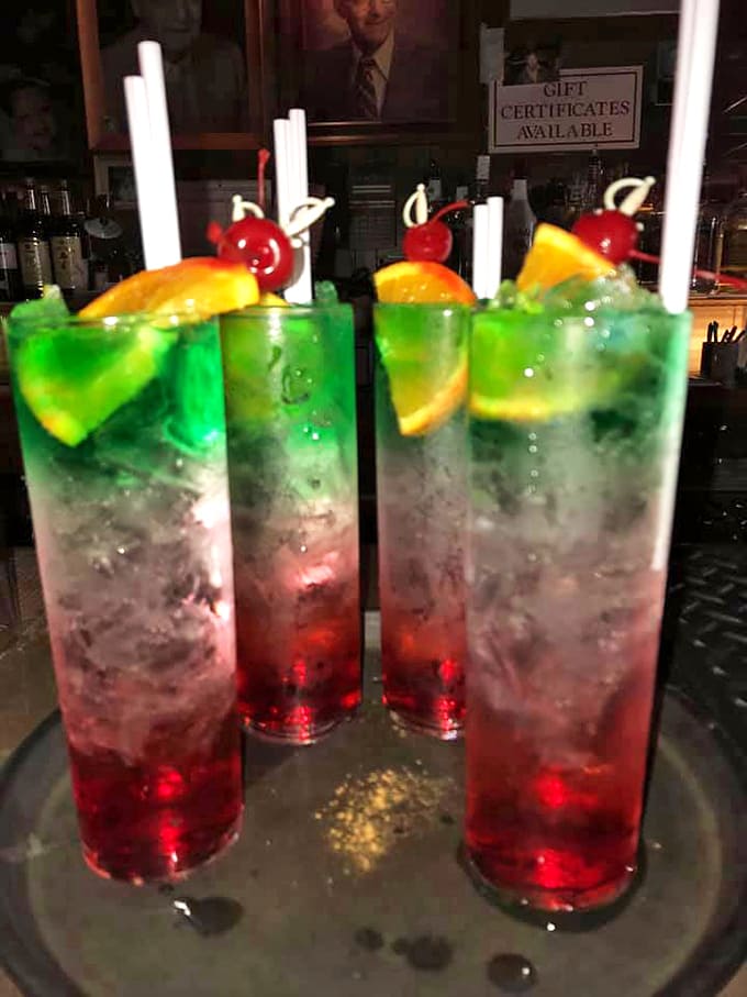 Liquid rainbows in a glass &ndash; red transitioning to vibrant green, garnished with citrus and cherries. The kind that make nearby tables ask, "What is THAT?"