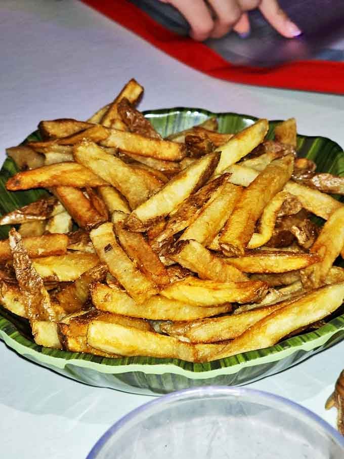 Golden, perfectly seasoned fries served in a tropical leaf-shaped dish. They're crispy on the outside, fluffy inside, and utterly impossible to stop eating once you start.
