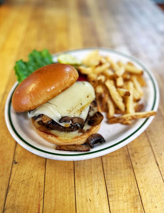 The Mushroom Swiss Burger arrives like a monument to excess, demanding both strategic planning and extra napkins.