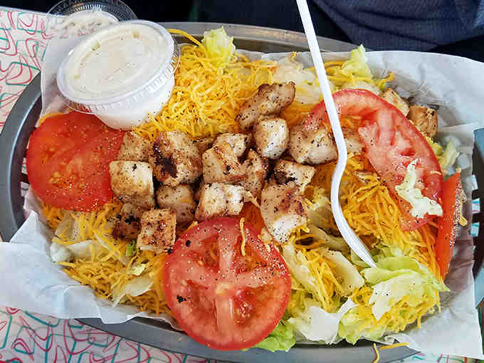 The grilled chicken salad offers a lighter option without sacrificing flavor – fresh greens, juicy tomatoes, and perfectly seasoned chicken served in a nostalgic metal dish.