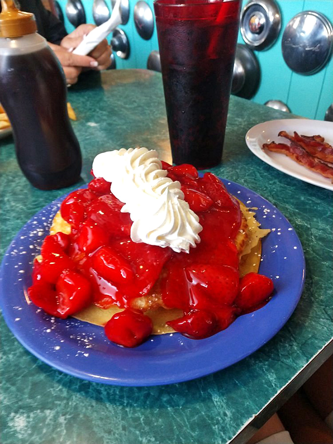 Belgian waffles buried under strawberries and whipped cream, because sometimes breakfast needs to look like a celebration of life itself.