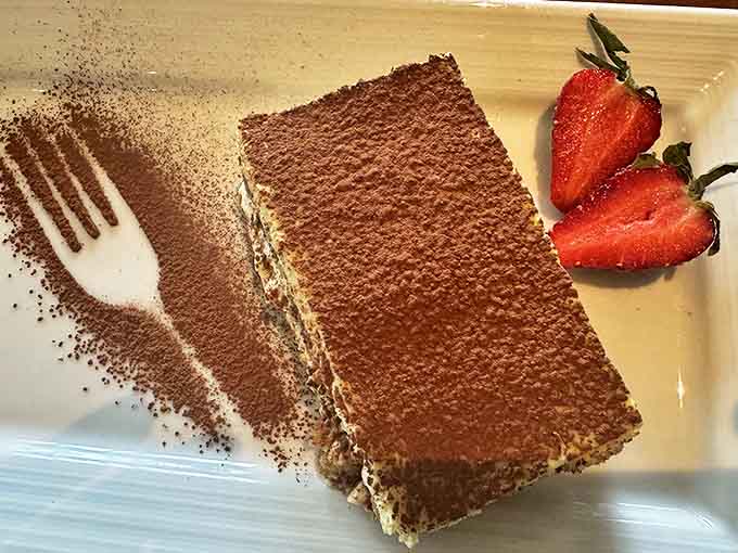 Classic tiramisu dusted with cocoa and paired with fresh strawberries &ndash; the sweet finale to an Italian feast.
