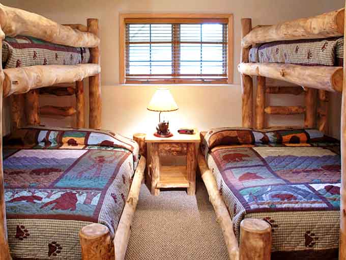 Log-crafted bunk beds transform ordinary bedtime into woodland adventures, with bear-themed quilts that practically guarantee northwoods dreams.