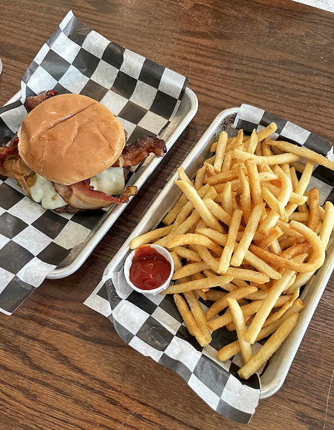 The burger arrives on a checkered paper-lined tray like a delicious time capsule from an era when food didn't need to be complicated to be perfect.