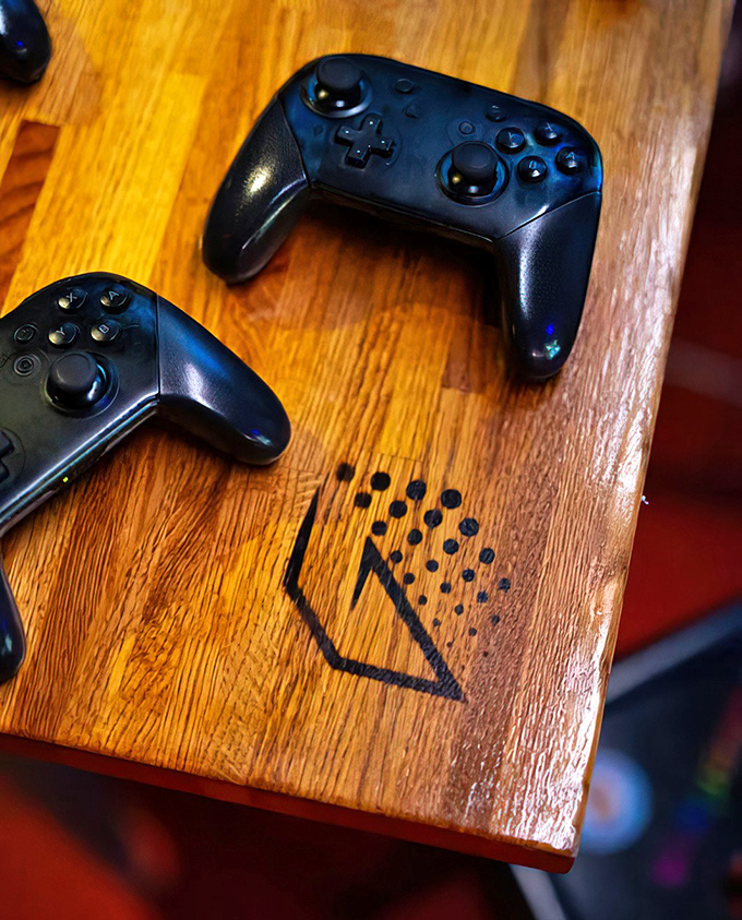 Nintendo Switch controllers await on custom wooden tables, proving Glitch Bar honors gaming history while embracing its present and future.