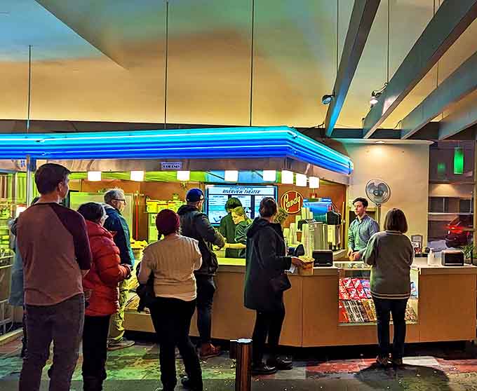 The concession stand glows with blue-neon promise, where popcorn still comes with real butter and doesn't require a second mortgage.