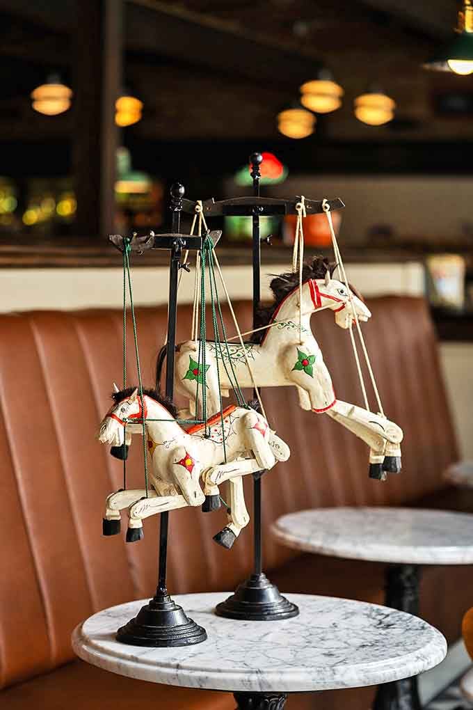 Wooden marionette horses frozen mid-gallop, their painted faces and jointed limbs harkening back to simpler entertainment that still somehow captivates modern eyes.