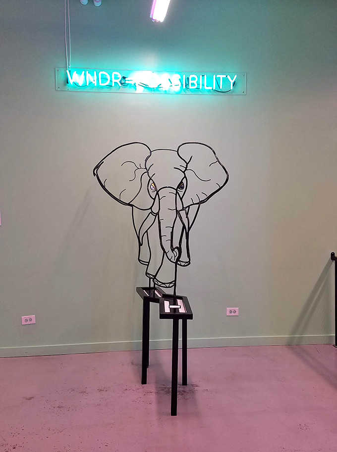 Wonder Possibility glows in neon above a minimalist elephant wire sculpture, proving sometimes the simplest designs make the strongest statements.