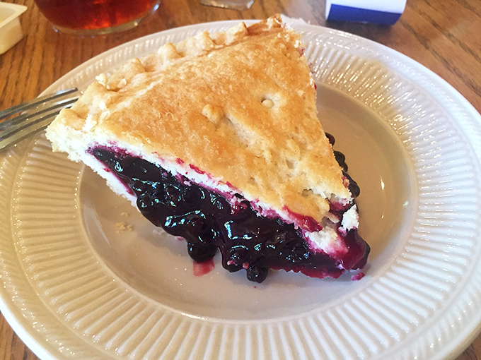 Blueberry pie bursting with fruit that pops with bright, tangy sweetness against the backdrop of buttery, flaky crust.