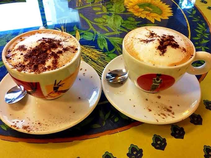 Two cappuccinos dusted with cocoa powder like they're wearing little chocolate berets – coffee that respects you too much to be mediocre.