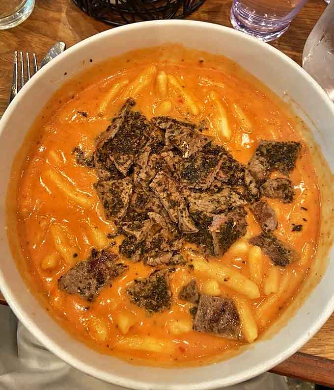 Cavatappi pasta swimming in creamy vodka sauce cradles tender blackened meat, proving comfort food can be sophisticated without being pretentious.