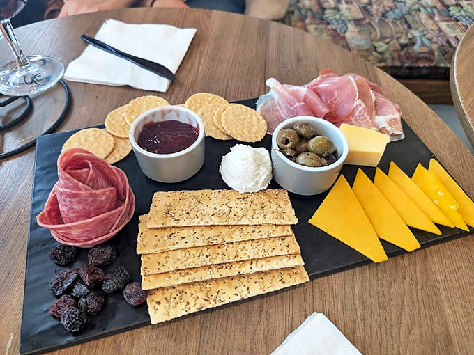 Charcuterie Board: A slate canvas showcasing the perfect wine companions &ndash; creamy cheeses, paper-thin prosciutto, and savory crackers ready for your pairing adventure.