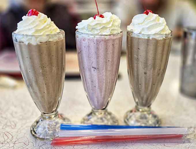 Classic milkshakes topped with whipped cream and cherries, thick enough to require effort but worth every calorie-laden sip.