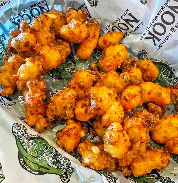 These golden nuggets of joy deliver that signature Wisconsin squeak, transformed by Minnesota magic into the perfect burger prelude.