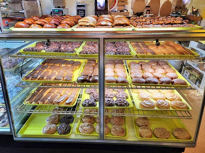 The display case presents a museum of edible art, with trays of pastries arranged like precious exhibits waiting to be admired.