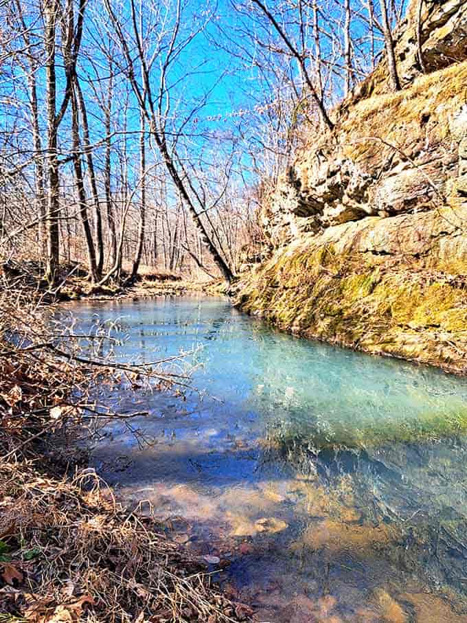 Crystal clear waters reflect the ancient stone walls, doubling the visual impact of this hidden stream tucked between towering cliffs.