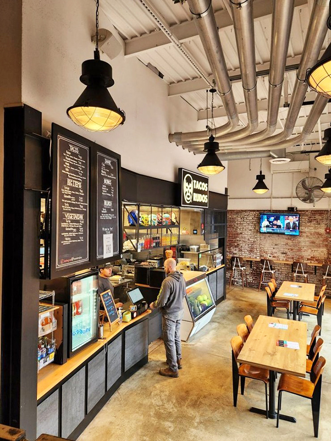 Tacos Rudos' counter showcases the industrial-meets-culinary aesthetic, with exposed pipes overhead and mouthwatering Mexican cuisine below.