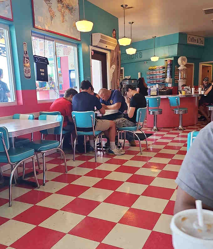 The diner buzzes with conversation as patrons enjoy their meals in a space where strangers become friends over shared tables and shared stories.