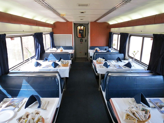 The dining car awaits passengers with white tablecloths and place settings, promising meals with a side of spectacular views.
