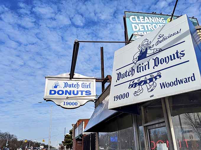 Under Michigan's blue skies, the Dutch Girl Donuts signage promises sweet salvation to all who enter this beloved Detroit institution.