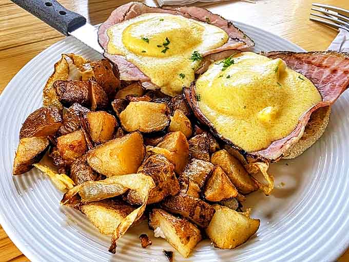 Eggs Benedict done right: perfectly poached eggs on Canadian bacon and English muffins, smothered in hollandaise and served with crispy home fries.