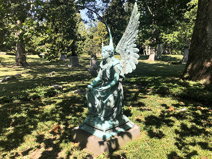 This serene angel statue keeps eternal watch, its weathered patina suggesting countless seasons of silent observation.