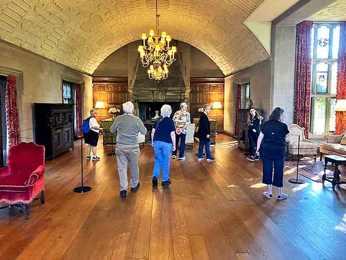 Visitors explore the grand hall where countless footsteps have polished the floors to a warm glow over decades.