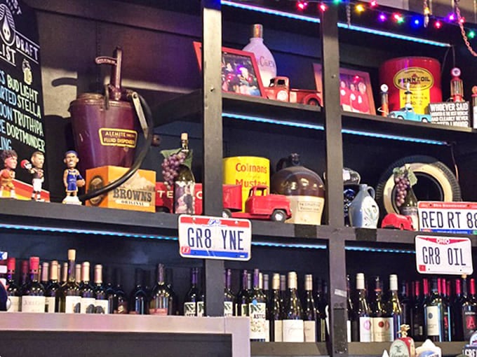 The bar area features license plates with clever automotive puns and shelves lined with vintage oil cans and collectible memorabilia.