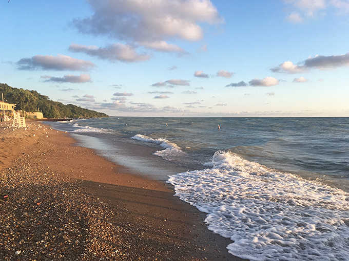 From this vantage point, the curve of shoreline reveals itself like a smile, with tiny figures creating a living mosaic against the sand.