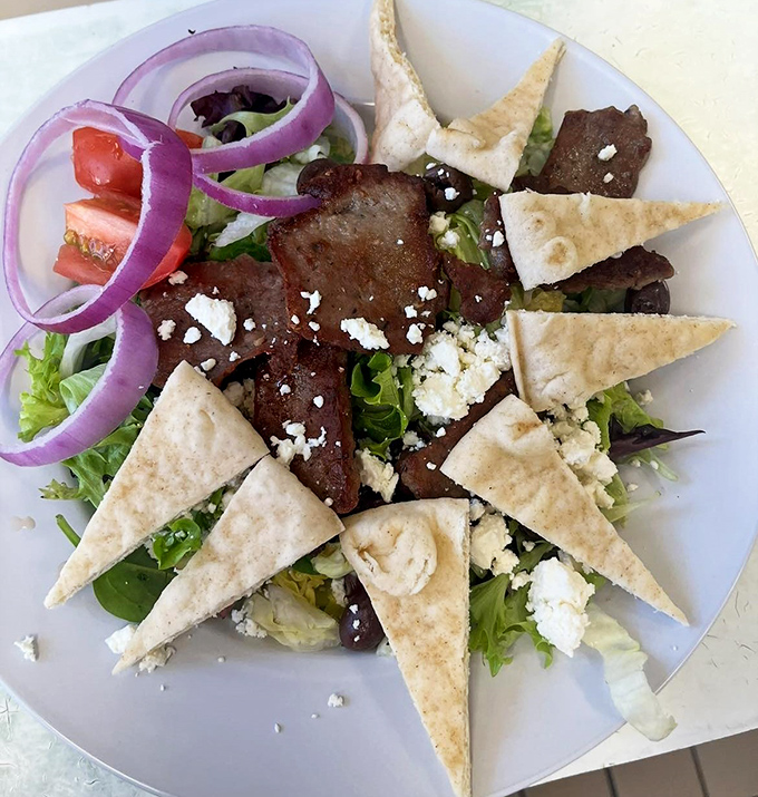 A Mediterranean vacation on a plate, where feta plays hide and seek with olives and tomatoes under a canopy of herbs.