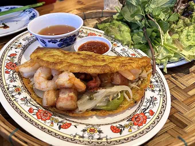 The Vietnamese crepe arrives golden and crackling, ready to be wrapped in lettuce with fresh herbs for textural perfection in every mouthful.